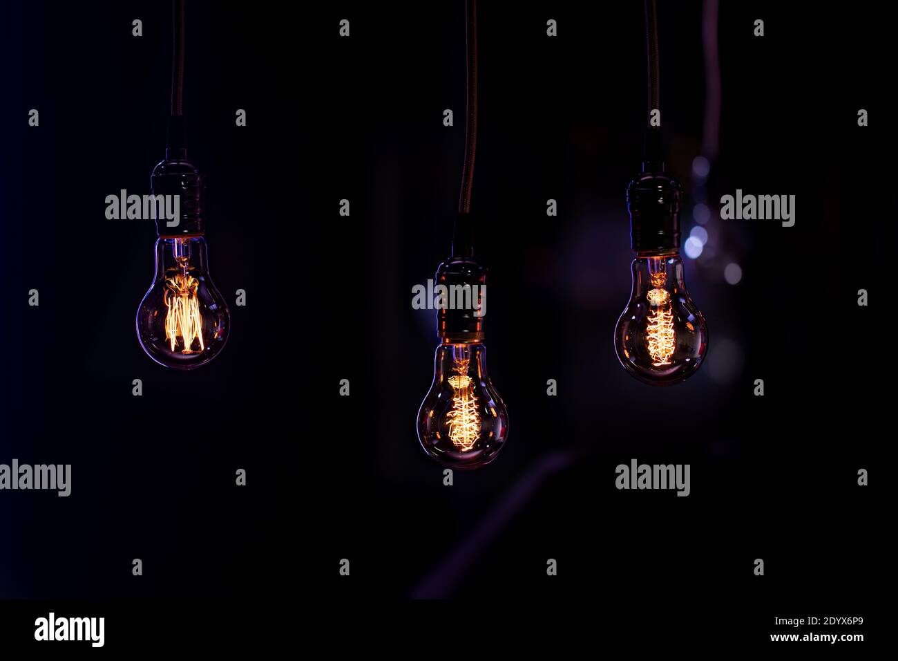 Three luminous lamps hang in the dark from the boke. Decor and ...