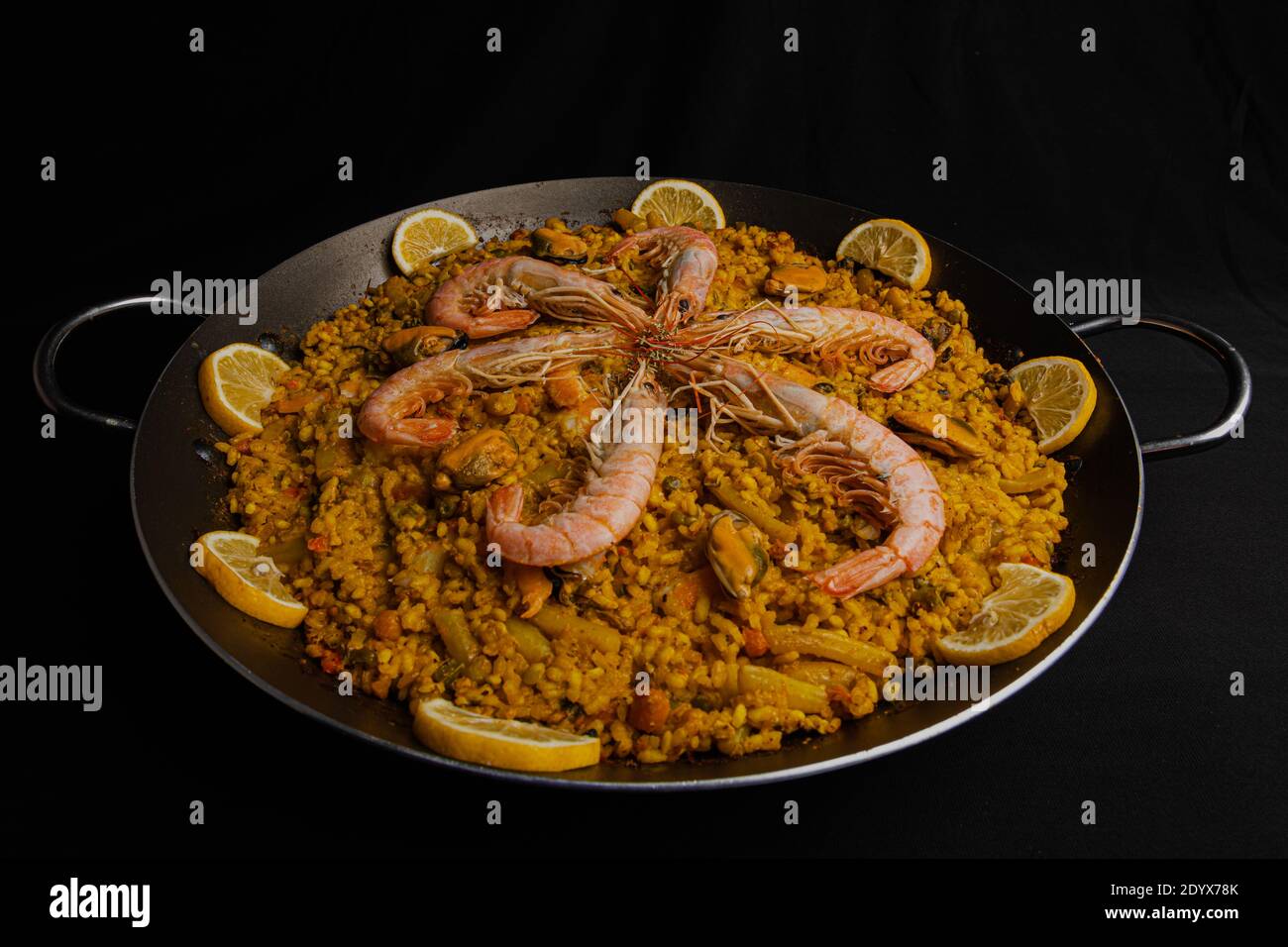 A typical Spanish Paella dish decorated with prawns and lemon. Made ...