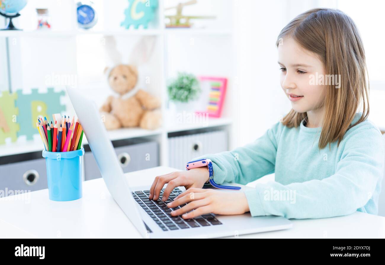 Cute little girl using computer in light room Stock Photo - Alamy