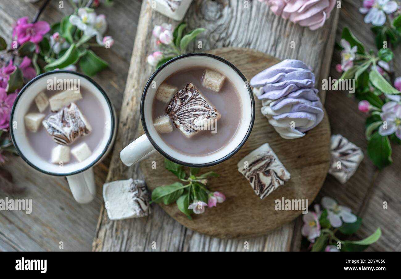 Top view of cocoa cups with tasty marshmallows near spring flowers ...