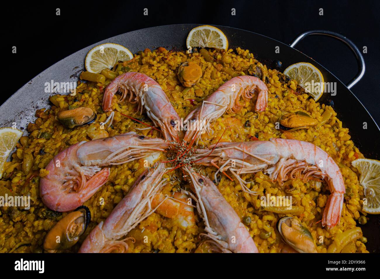 A typical Spanish Paella dish decorated with prawns and lemon. Made ...