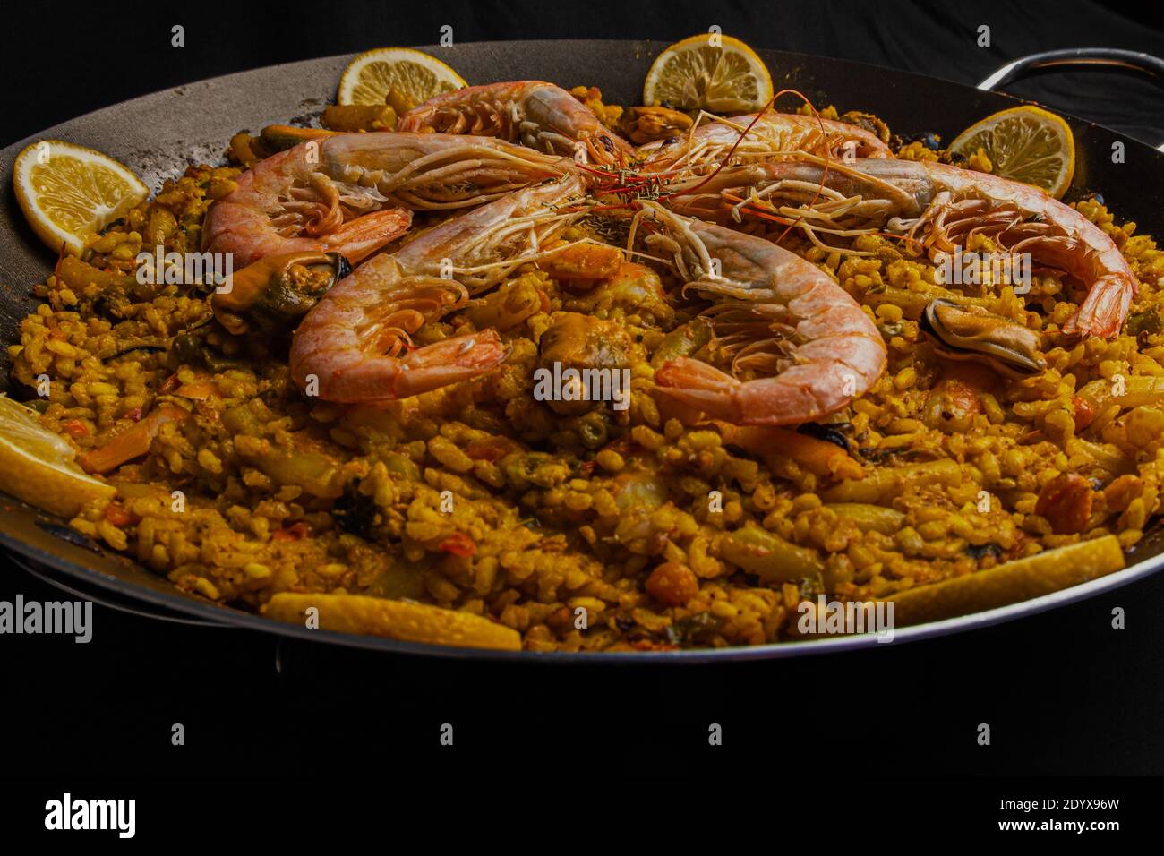 A typical Spanish Paella dish decorated with prawns and lemon. Made ...