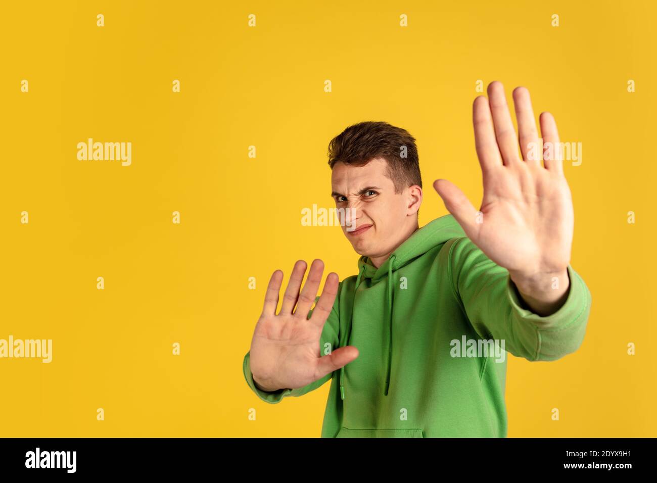 Stop, rejecting. Caucasian young man's portrait on yellow studio ...