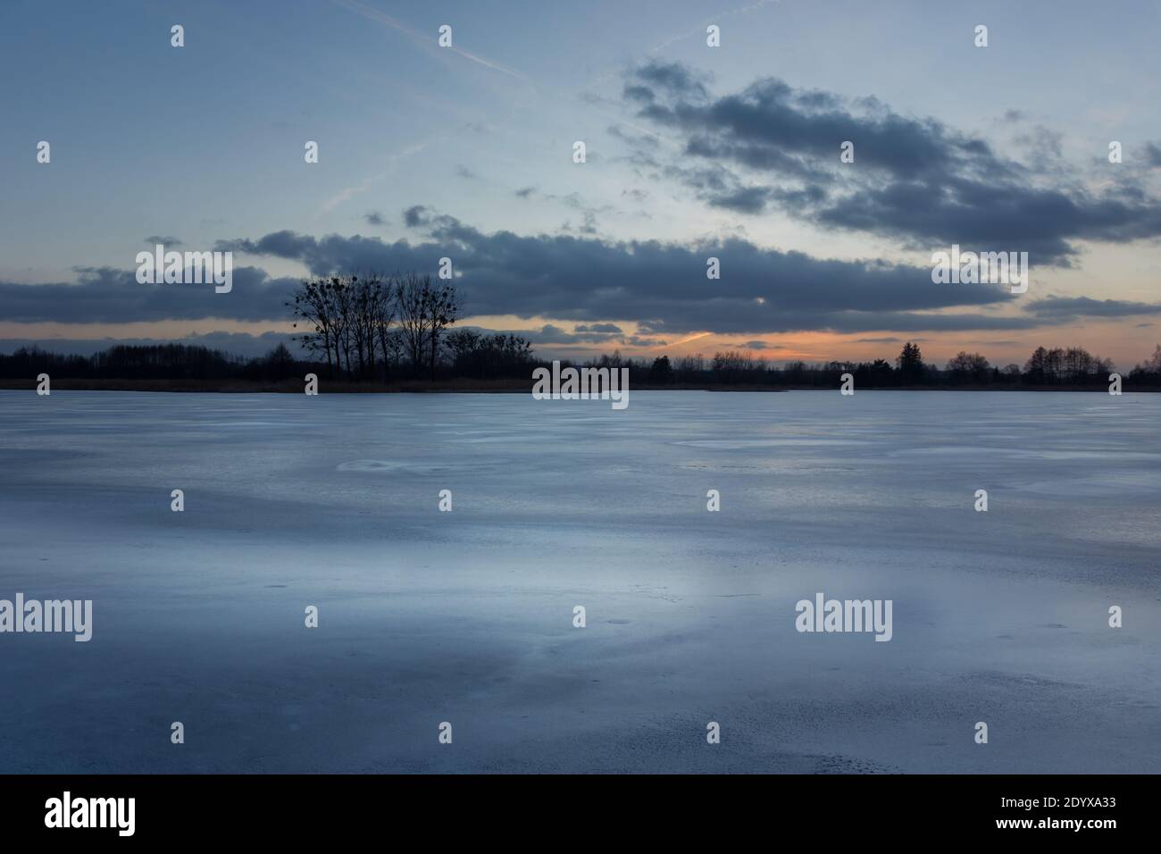 Frozen lake, trees on the horizon and an evening clouds Stock Photo - Alamy
