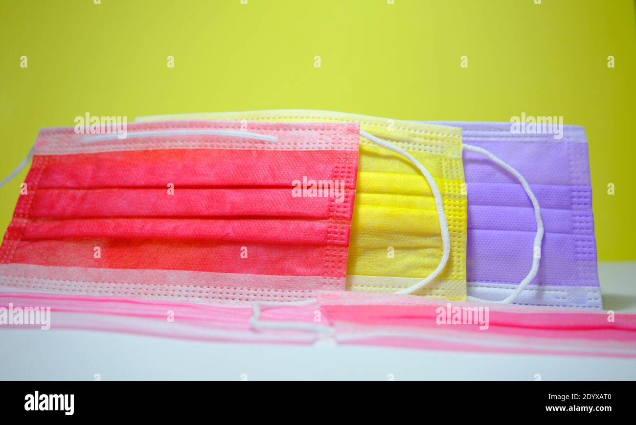 Colorful (red, yellow, purple, pink) medical masks on white ground and ...
