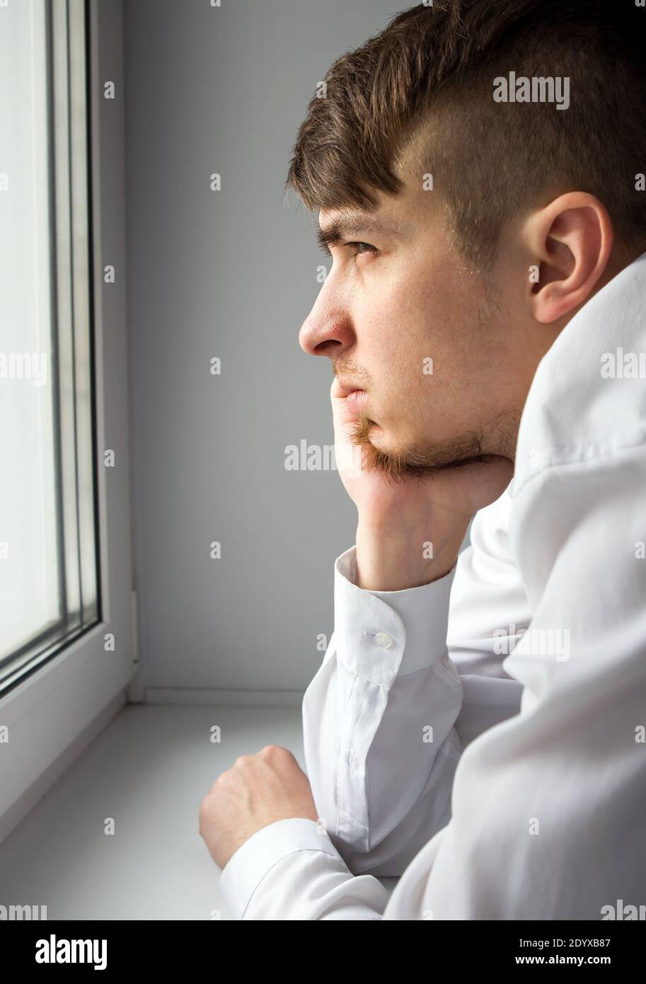 Sad Young Man by the Window in the Room Stock Photo - Alamy