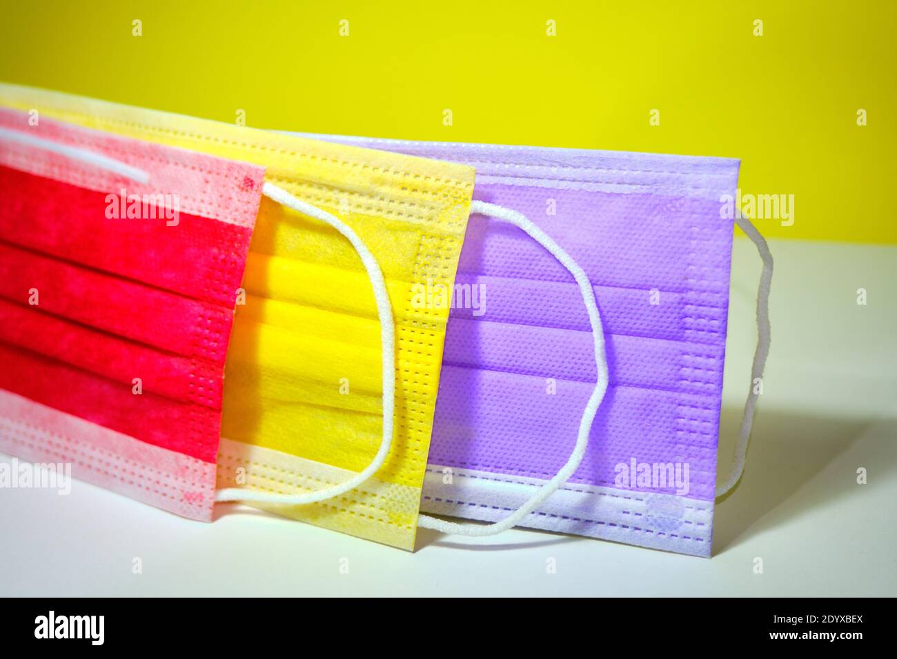 Colorful (red, yellow, purple, pink) medical masks on white ground and ...