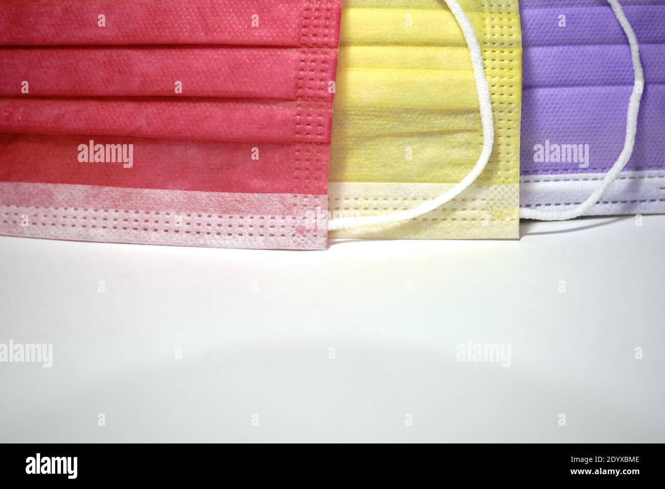 Colorful (red, yellow, purple, pink) medical masks on white ground and ...