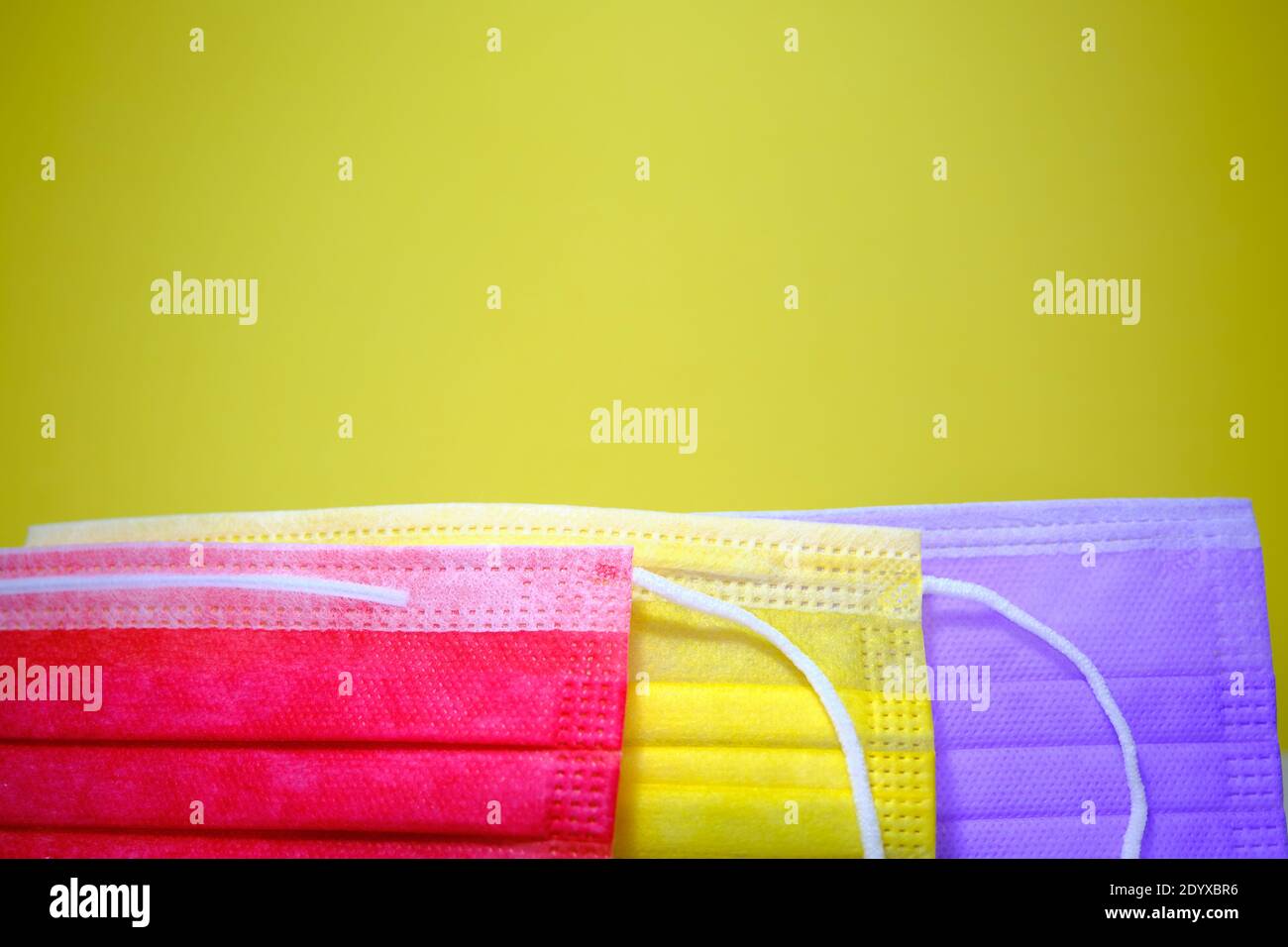 Colorful (red, yellow, purple, pink) medical masks on white ground and ...