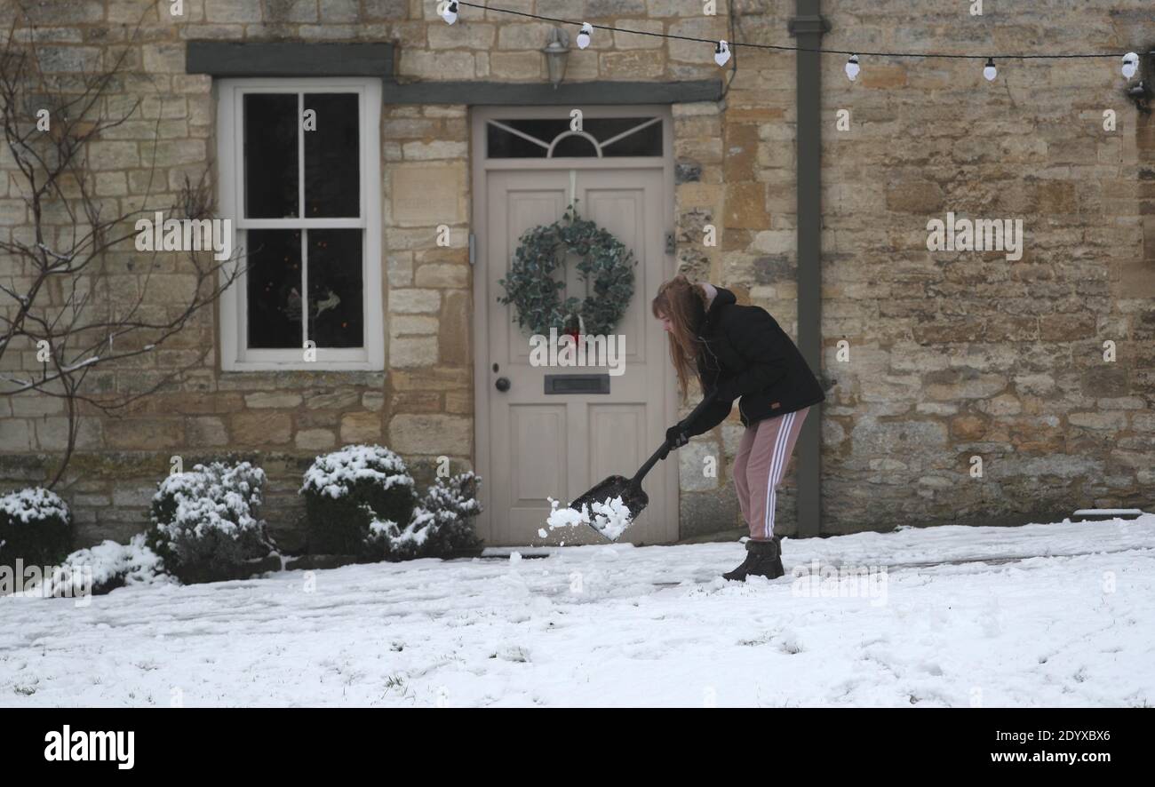 A woman clears snow from pathways in Burford, West Oxfordshire Stock ...