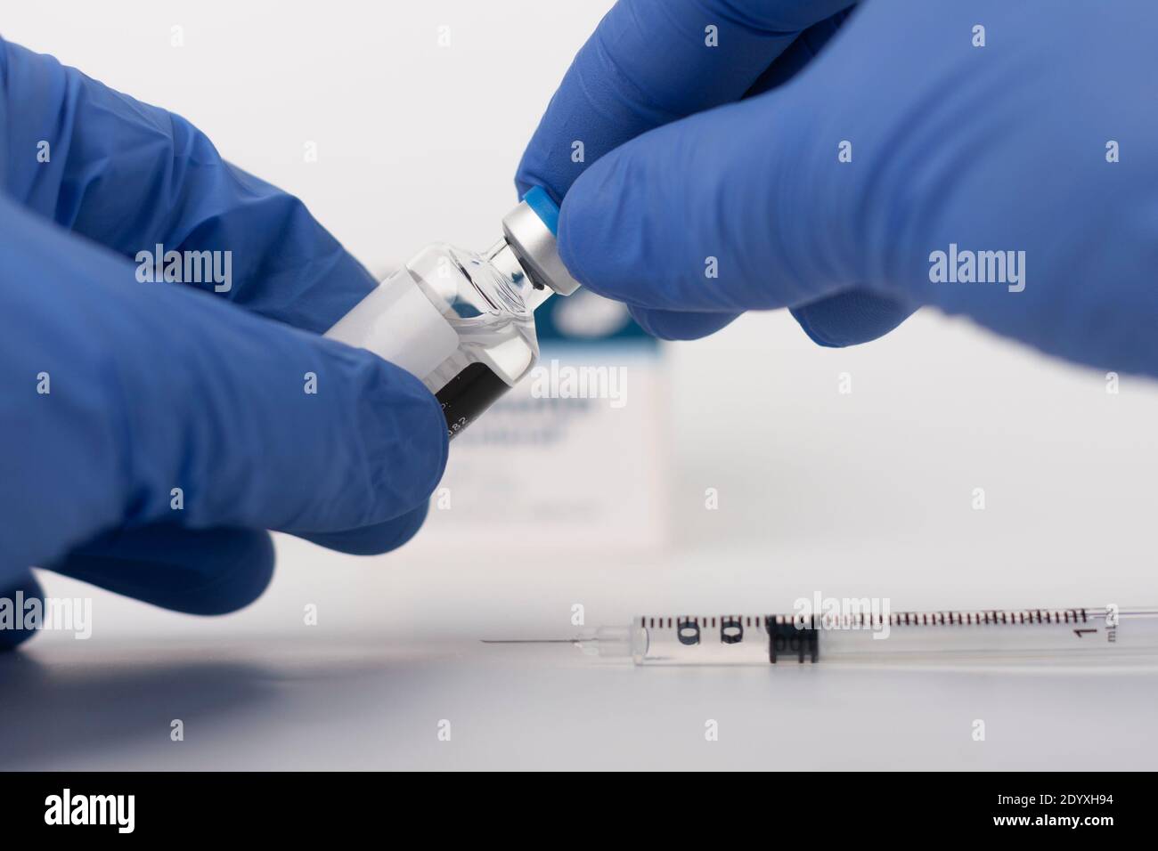 Human fingers in gloves, syringe with needle and Covid-19 vaccine vial ...