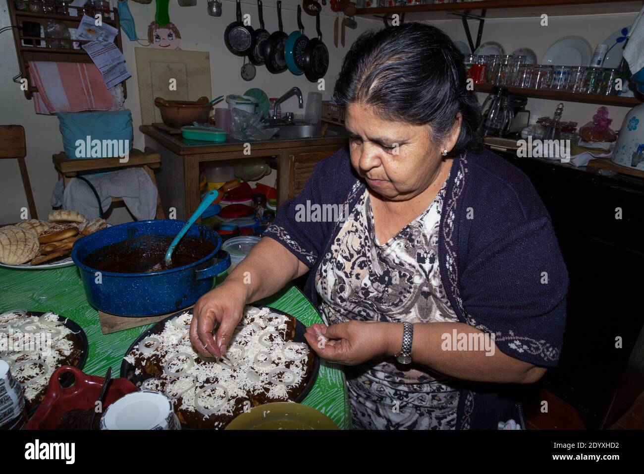 Senior Hispanic woman chef in a kitchen preparing mole enchiladas in a ...