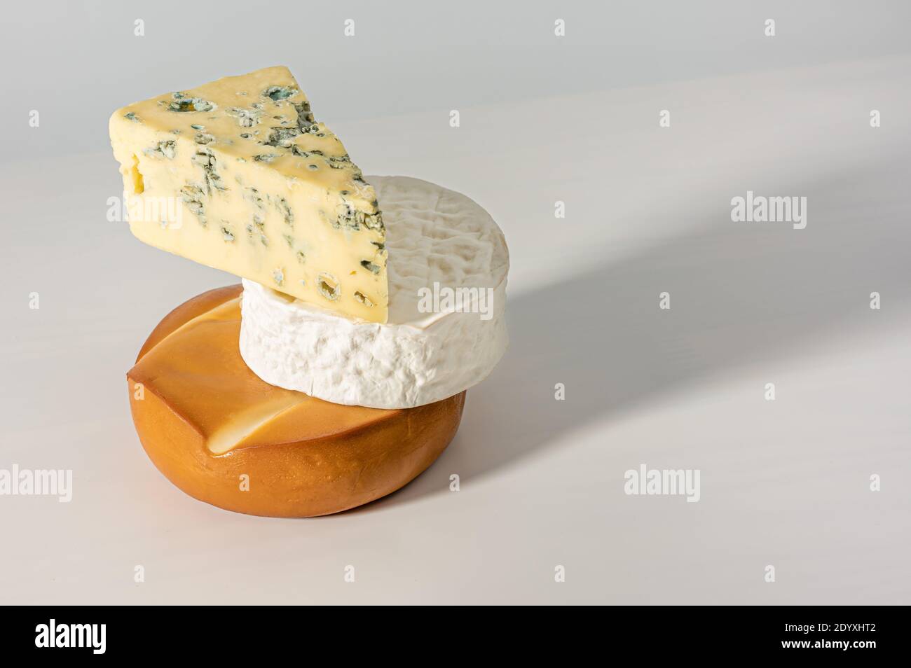 smoked cheese, brie and mouldy cheese are stacked on top of each other ...