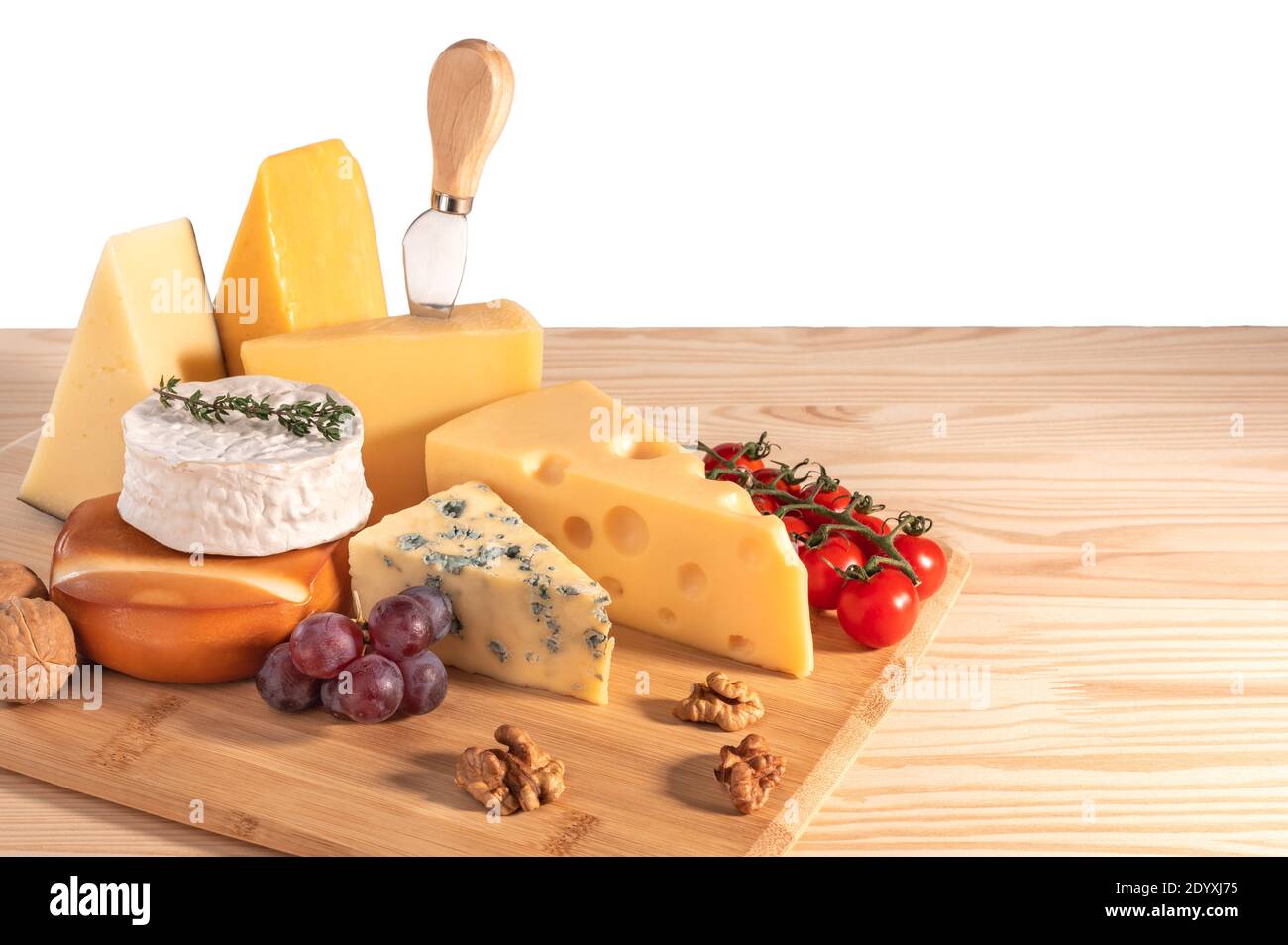 Assortment of different types of cheese with walnuts, tomato and grapes ...