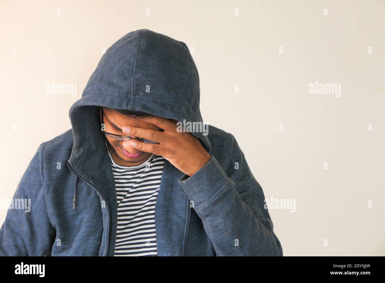 sad man in hood cover face with hands isolated in black Stock Photo - Alamy