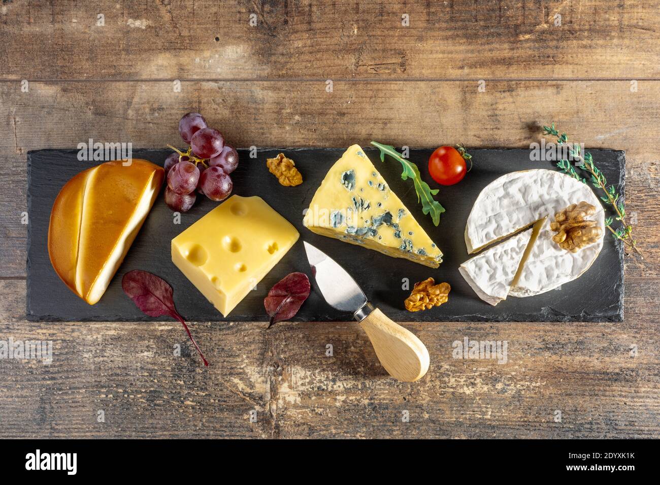 cheese plate. different cheeses laid out on long black stone Board ...