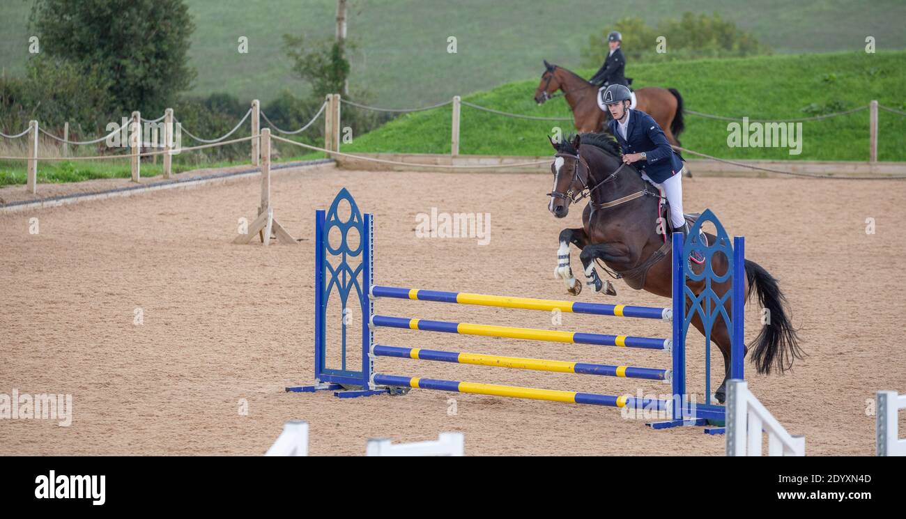 An equestrian rider on their horse jumping over a fence as they take ...