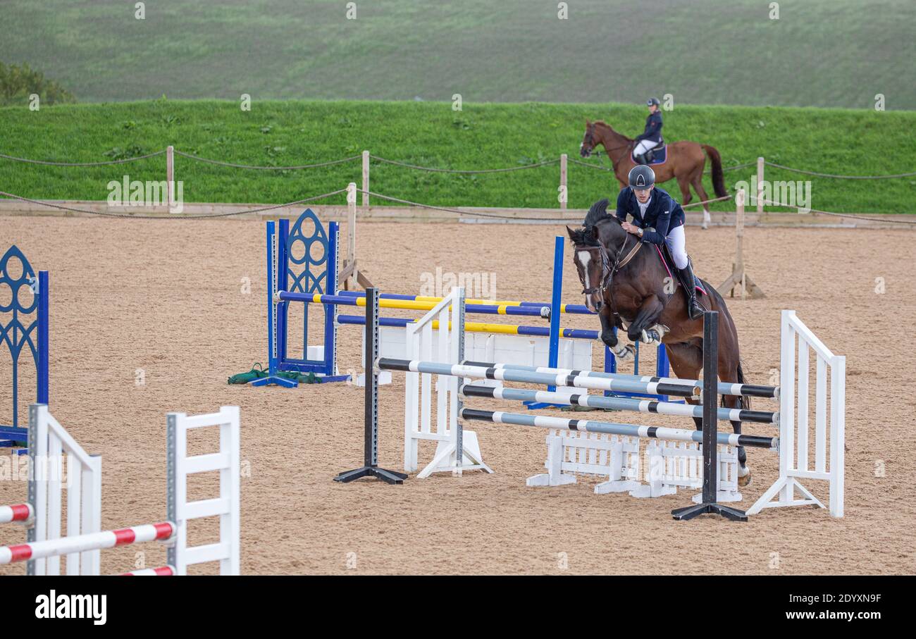 An equestrian rider on their horse jumping over a fence as they take ...