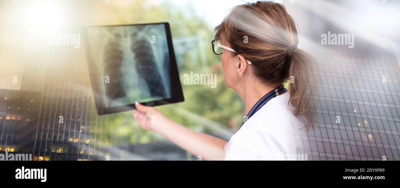 Female doctor examining x-ray report in medical office; multiple ...