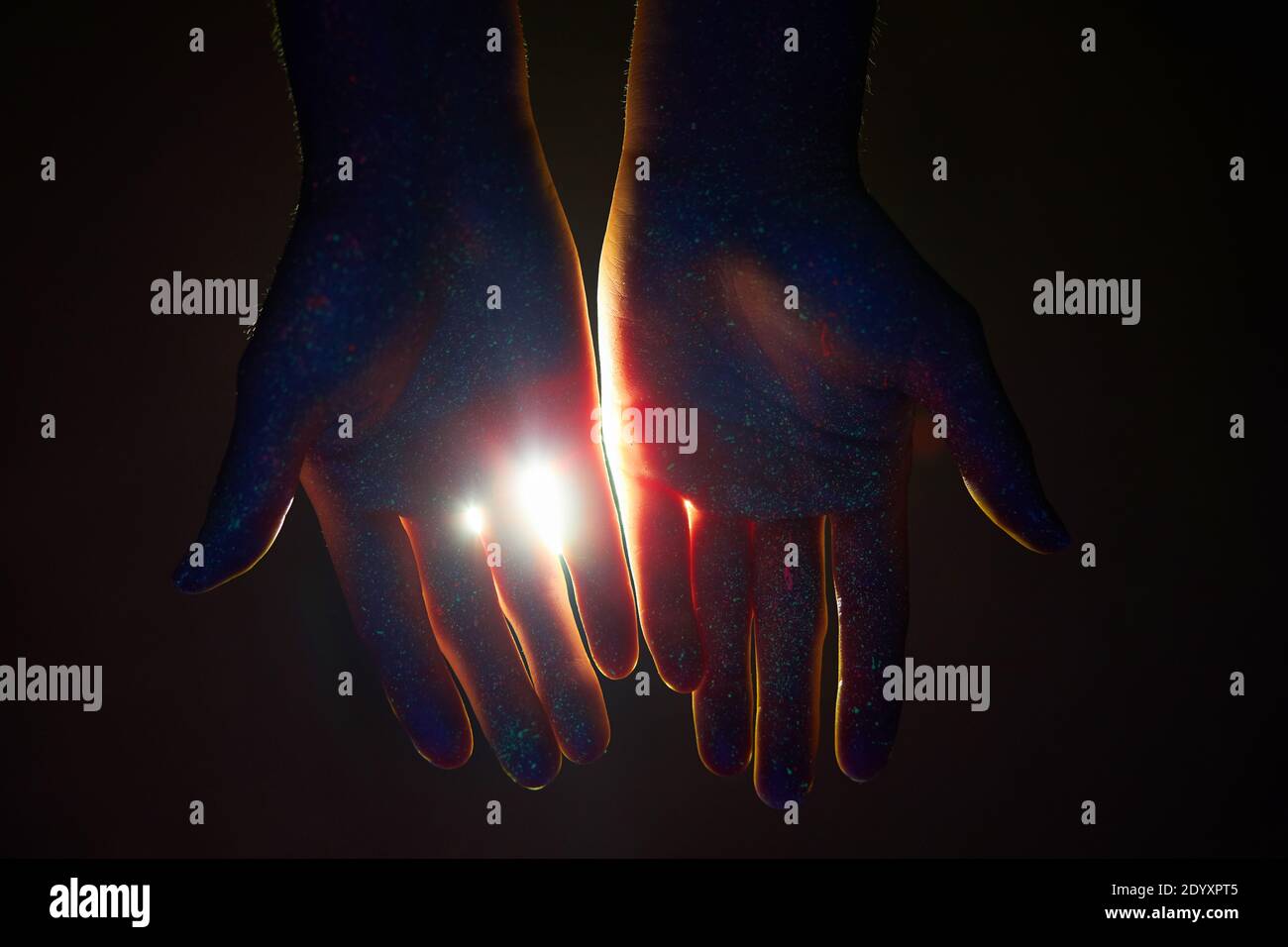 Beauty hands in ultraviolet light in drops of colored paint. Light ...