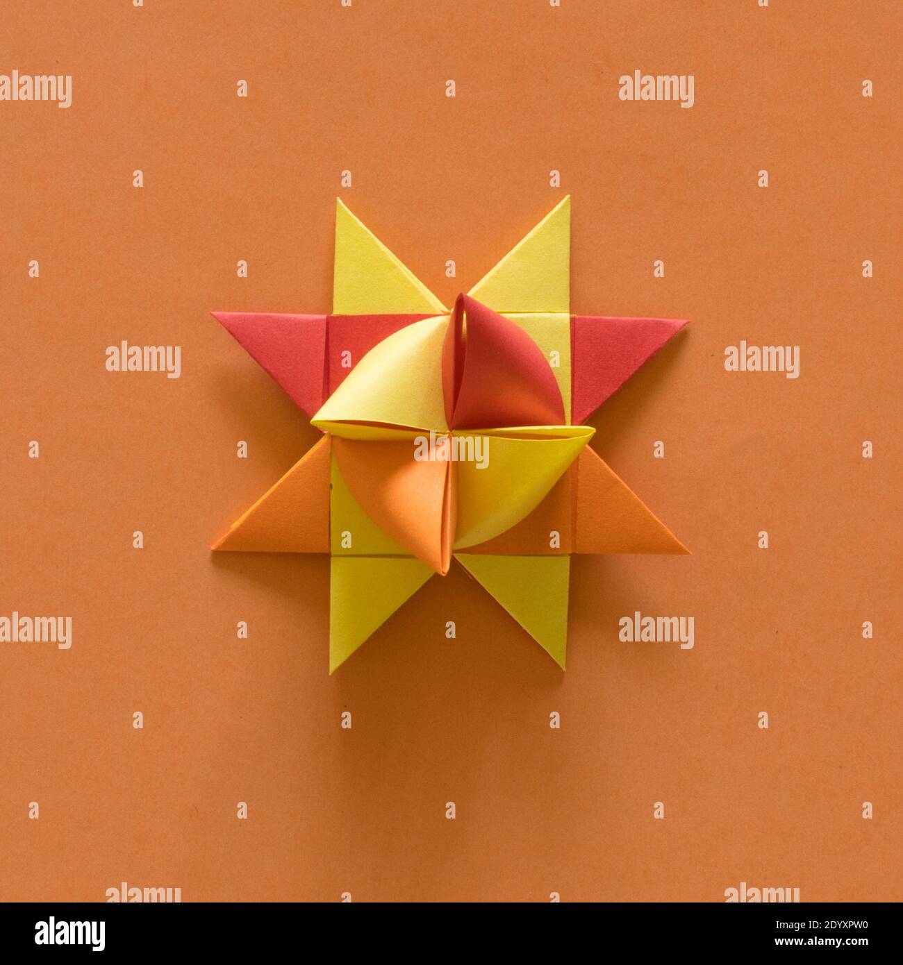 Top view of multicolor origami of 3D stars on an orange background ...