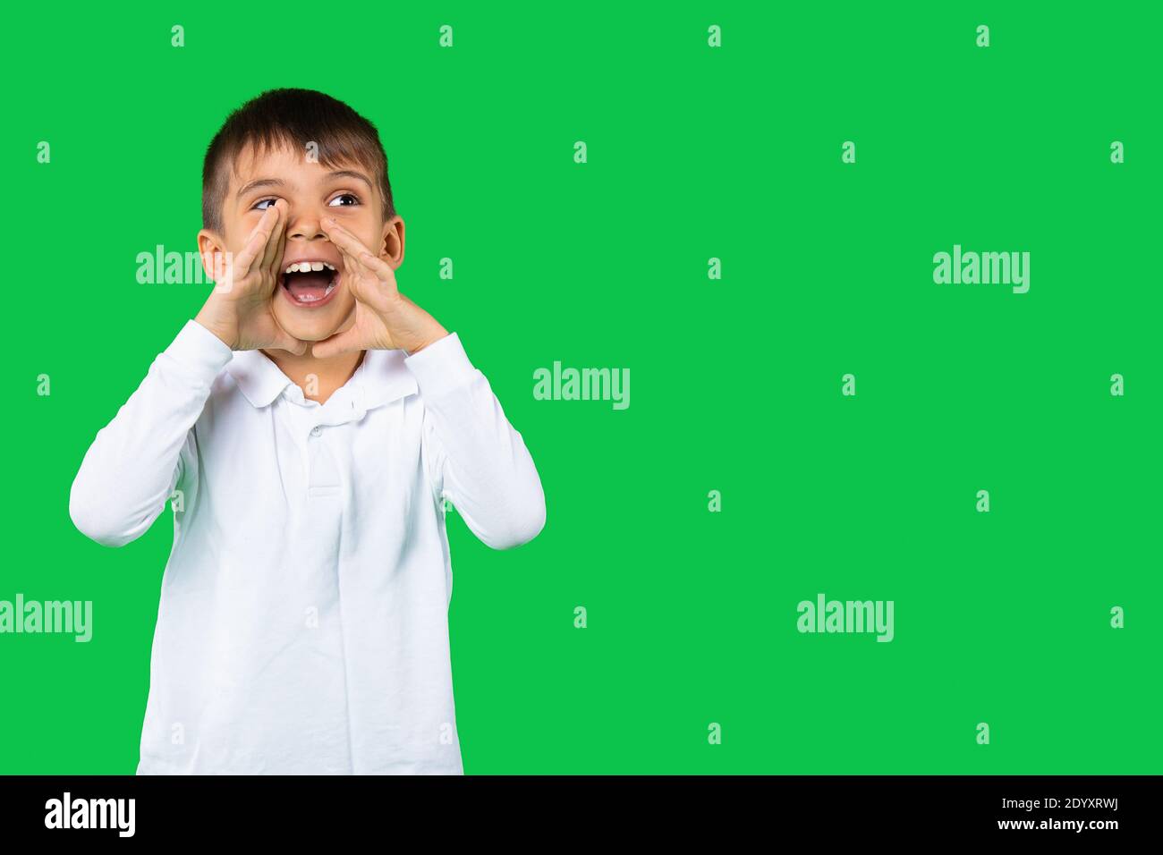 Portrait of a screaming boy looking side against a green background ...
