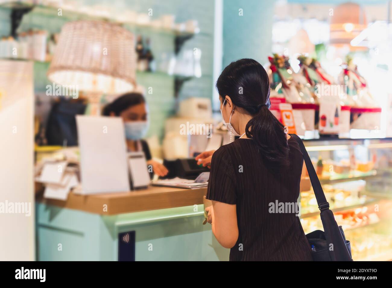 Woman with protective mask paying bill at cashier counter in cafe Stock ...