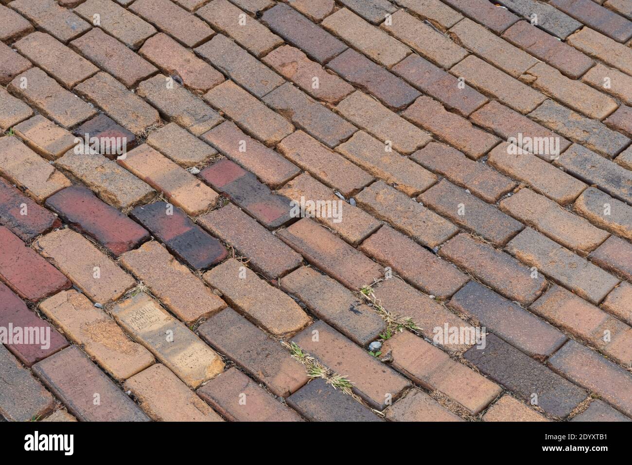 Background of roadway constructed of brick in mixed shades of red and ...