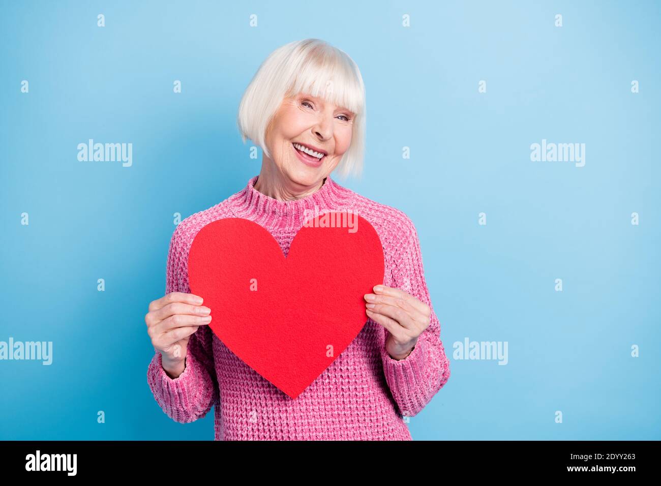 Photo portrait of cute old lady holding red heart postcard in two hands ...