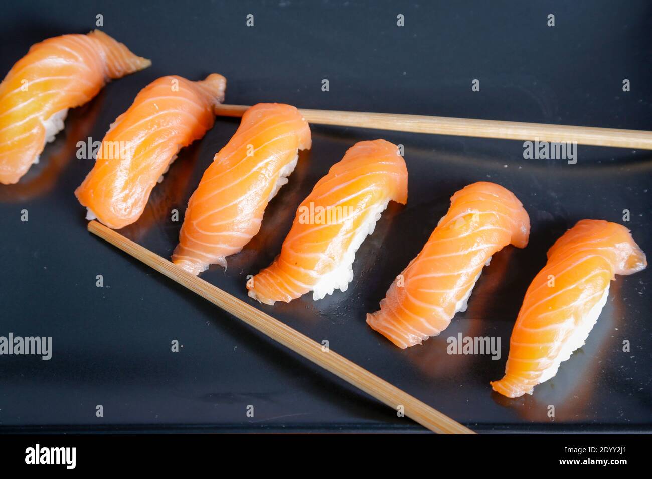 Salmon sushi typical of Japanese cuisine on black plate, natural light ...