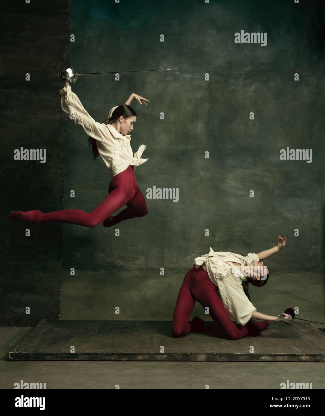 Attacking. Two young female ballet dancers like duelists with swords on ...