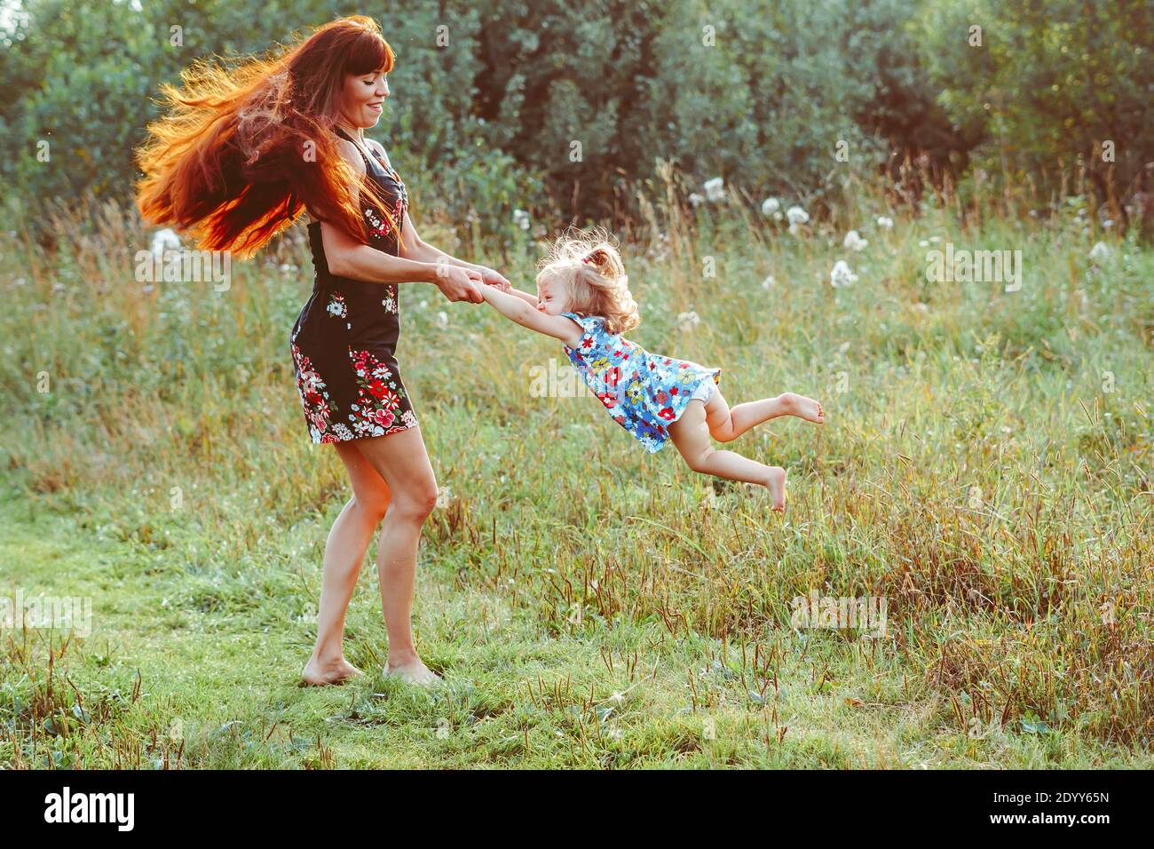 Cheerful mother rotating twisting making circle with her little ...