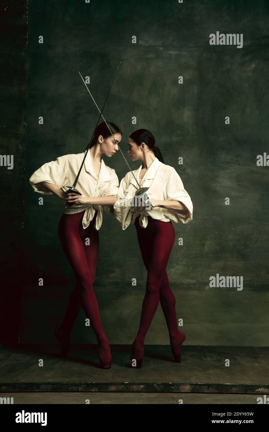 Emotions. Two young female ballet dancers like duelists with swords on ...
