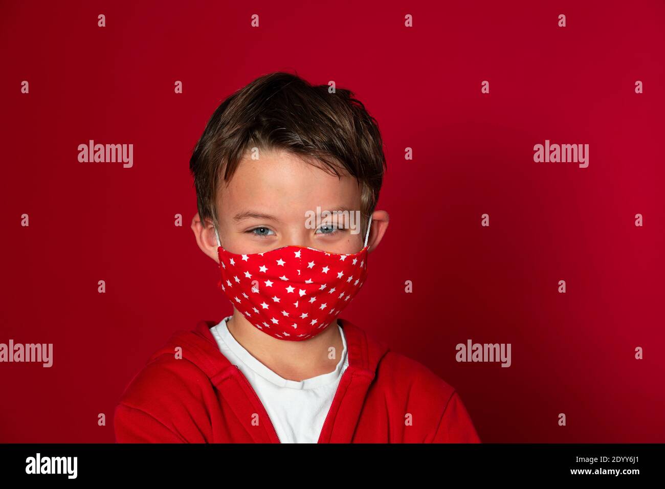 cool young schoolboy with red mask in front of red background wearing ...
