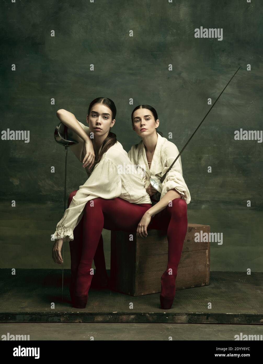 Duet. Two young female ballet dancers like duelists with swords on dark ...