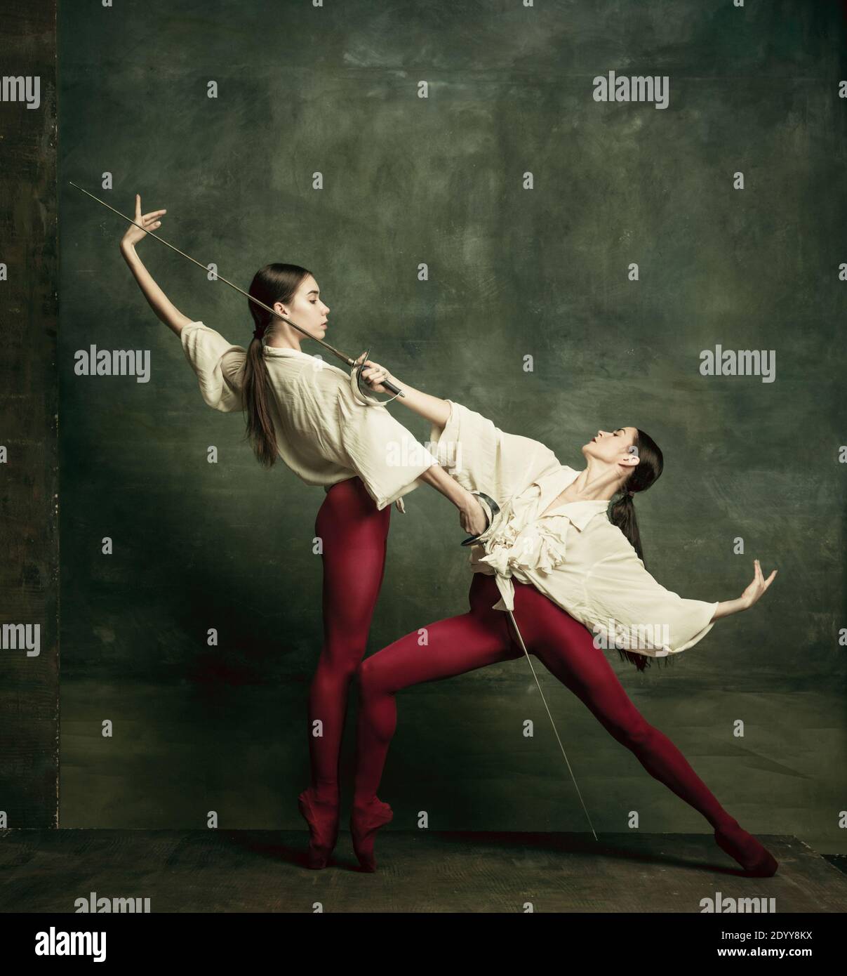 Pain. Two young female ballet dancers like duelists with swords on dark ...