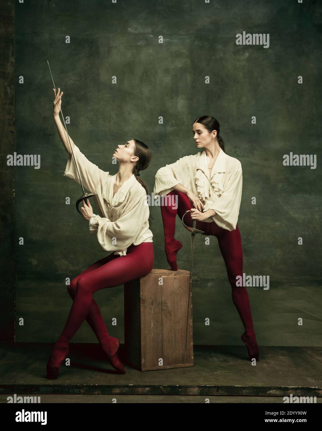 Romance. Two young female ballet dancers like duelists with swords on ...