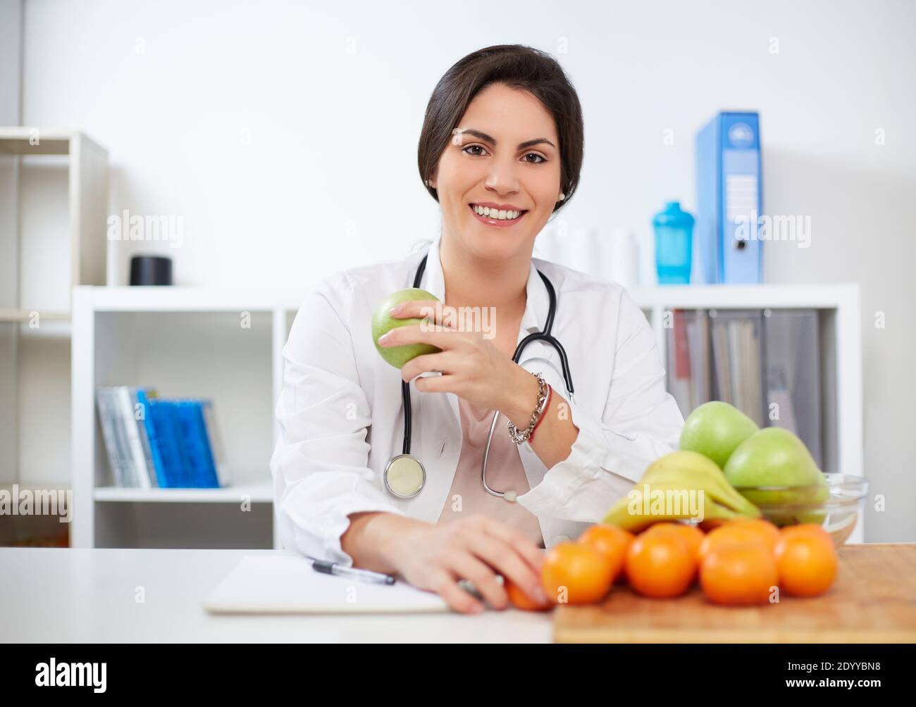 Beautiful smiling nutritionist looking at camera and showing healthy ...