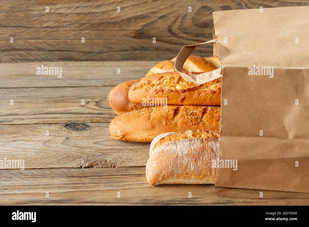 arranged french baguettes in paper bag and wheat on rustic wooden ...