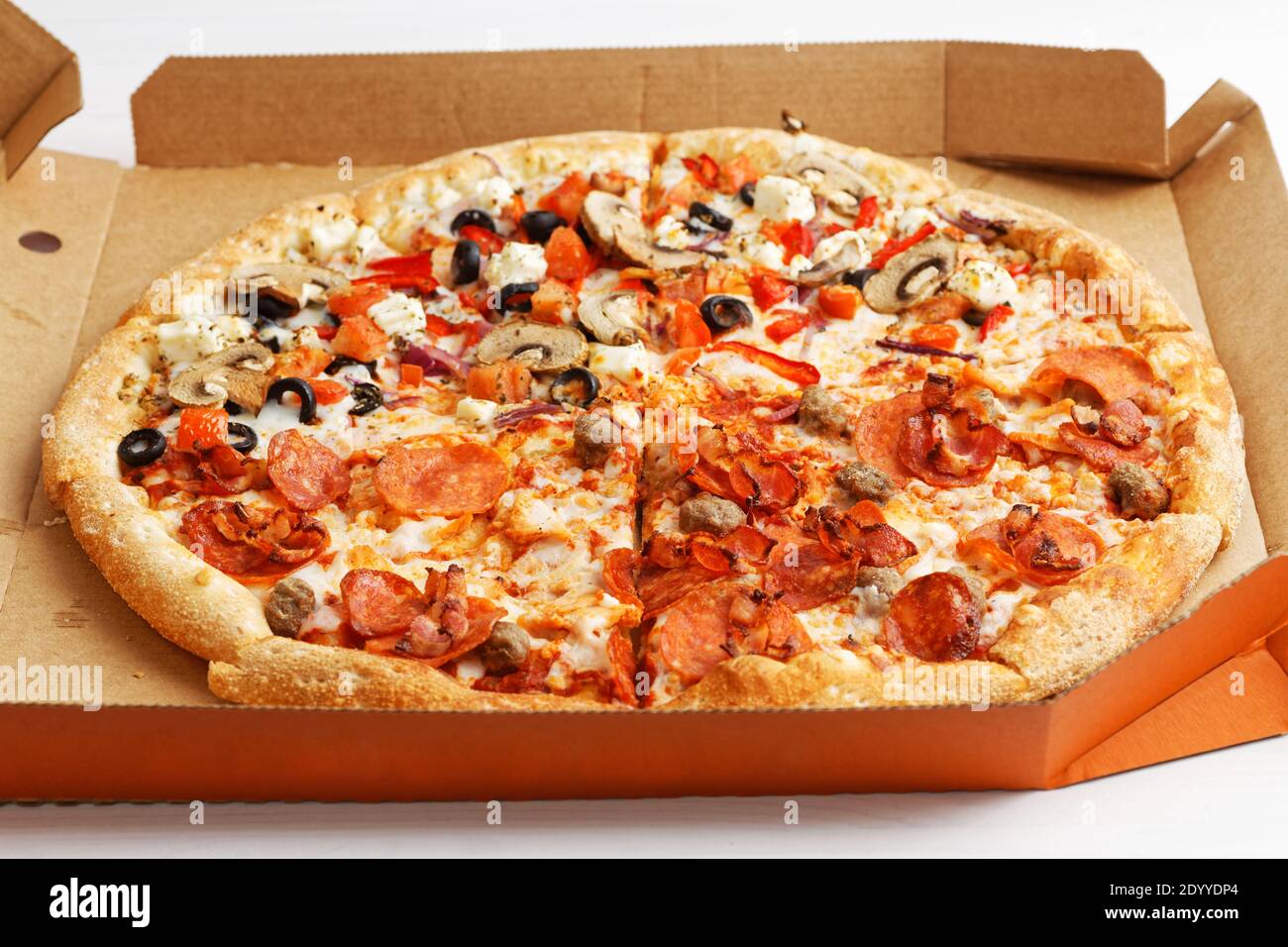 Half meat and half vegetable pizza on white wooden table. Angle view ...