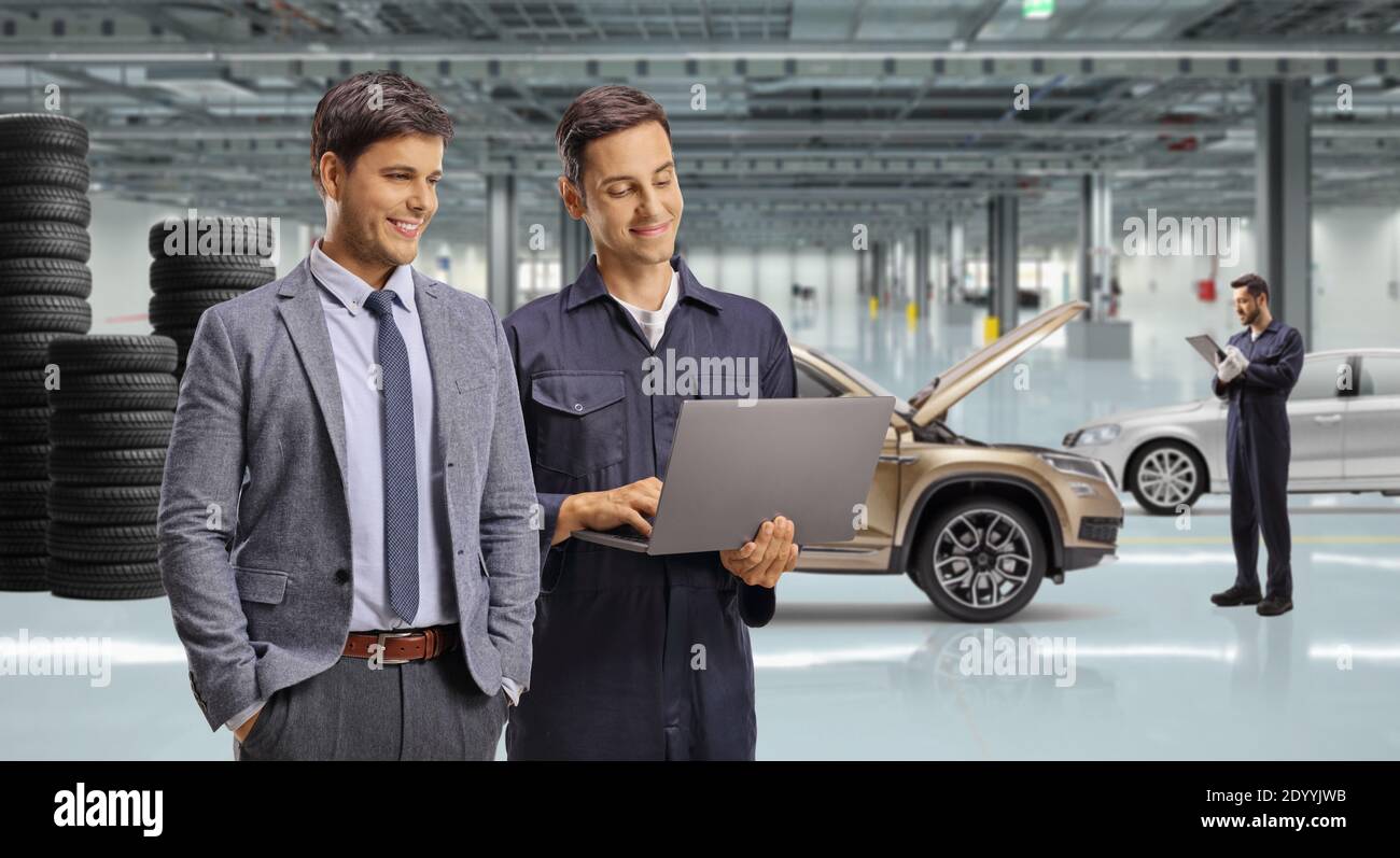 Customer and a mechanic with a laptop computer inside a car repair shop ...