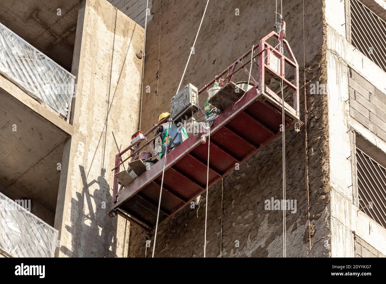 Construction cradle hanging at the wall of a house under construction ...