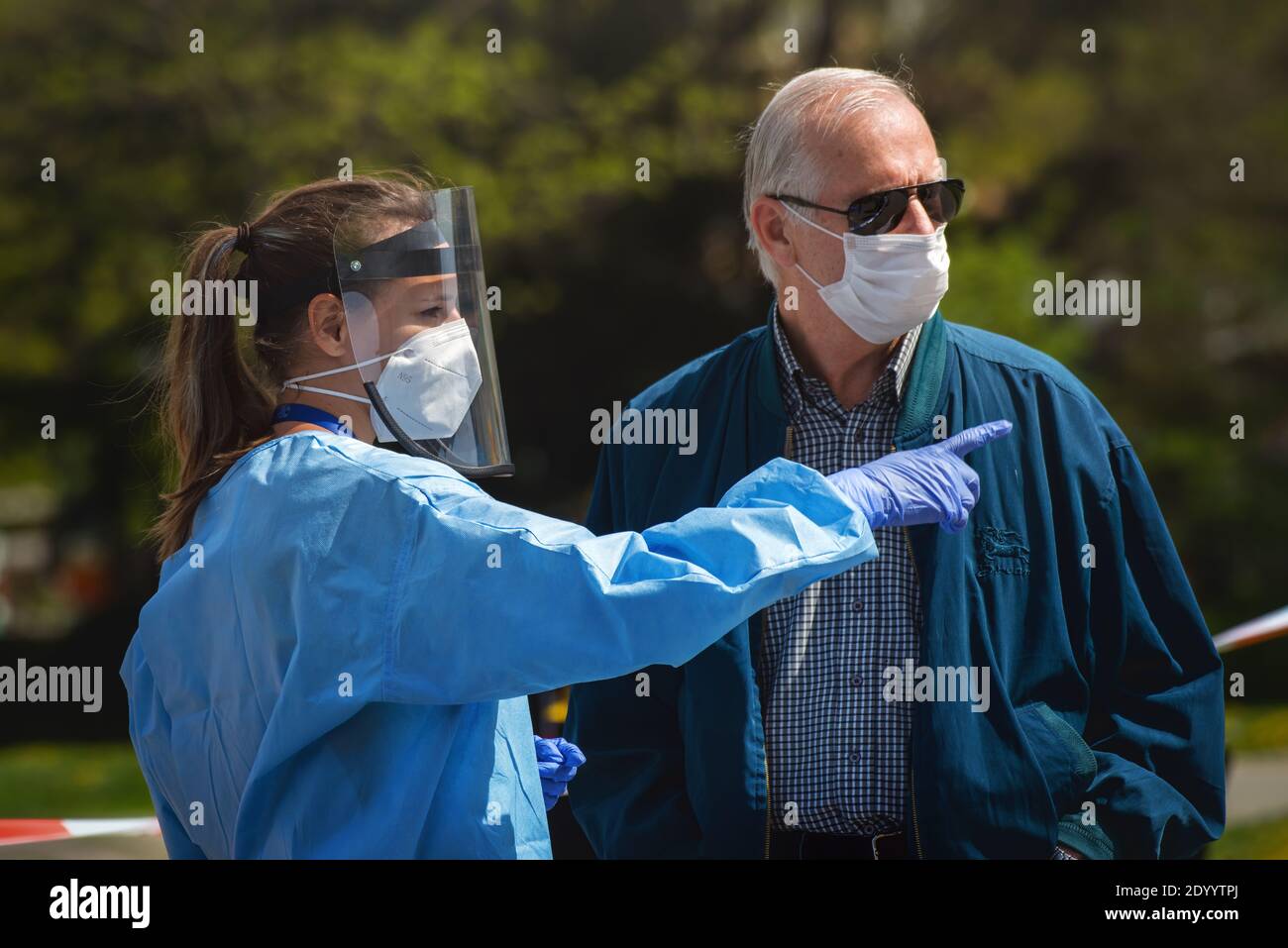 Medic pointing the old man with cloth face mask to the place where the ...