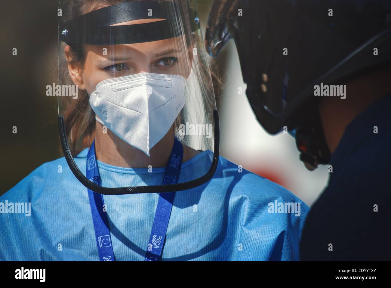 Young medic with a respirator and a plastic face shield talking to a ...