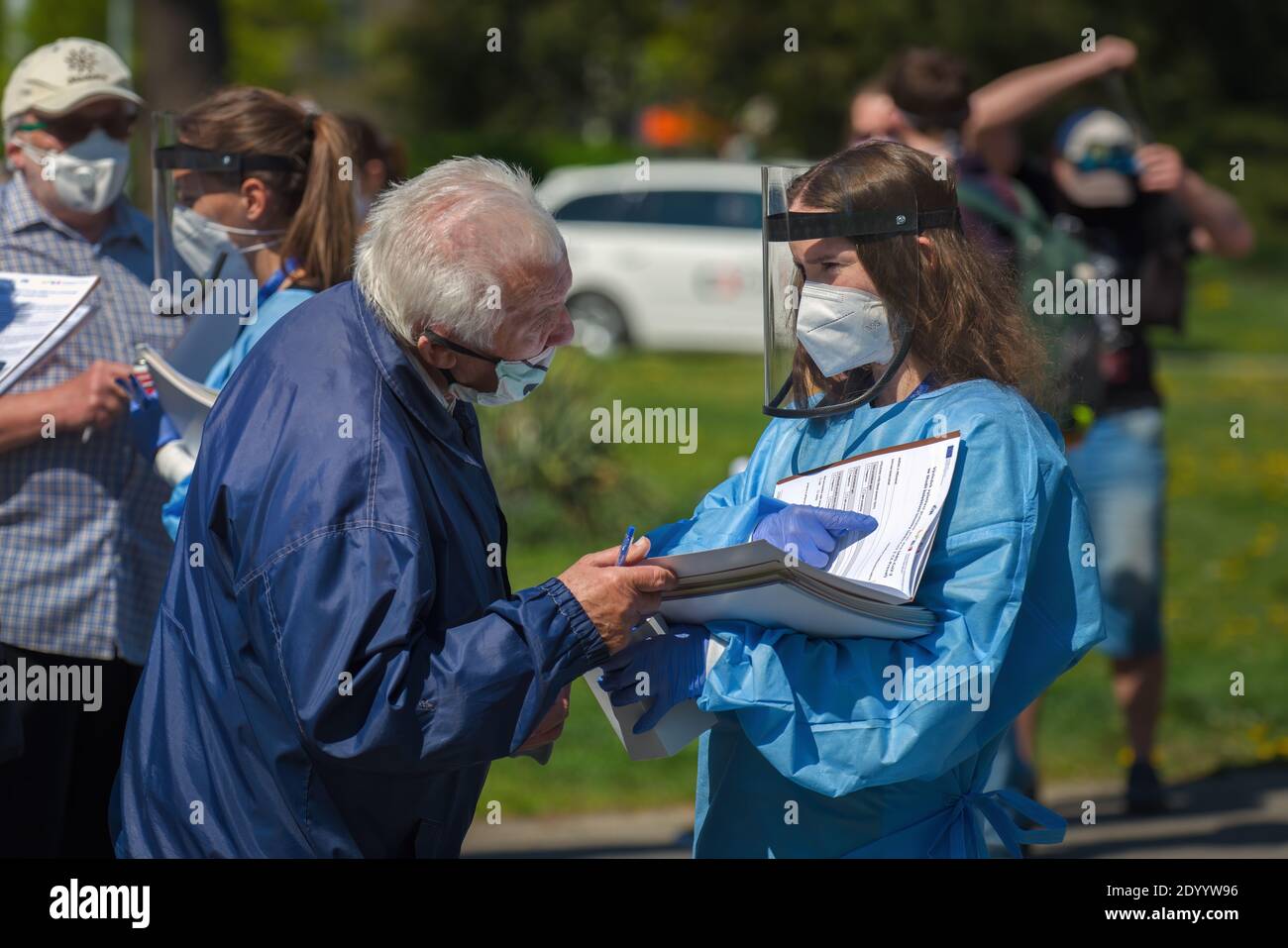 Young female medic explaining to an old man with a cloth face mask how ...