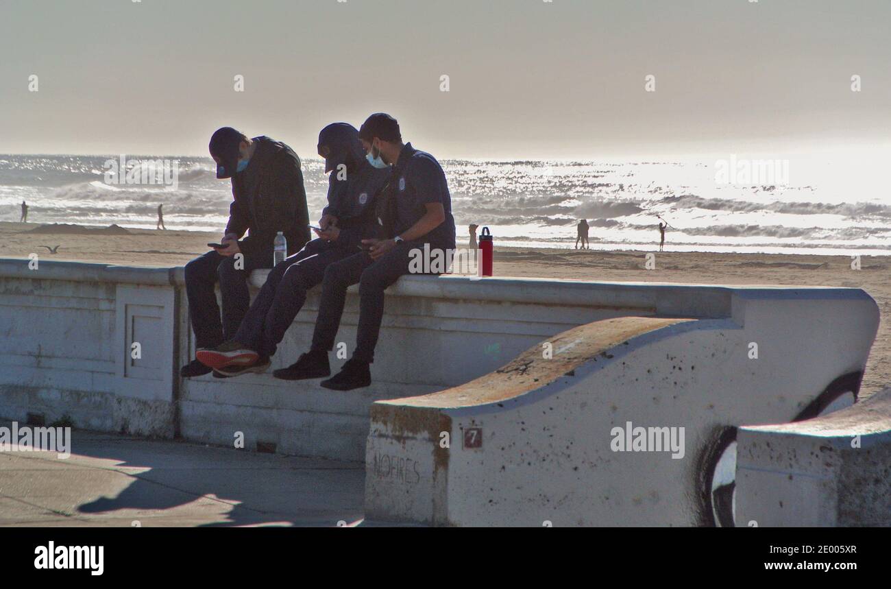 three male friends wearing covid 19 masks not social distancing sitting ...