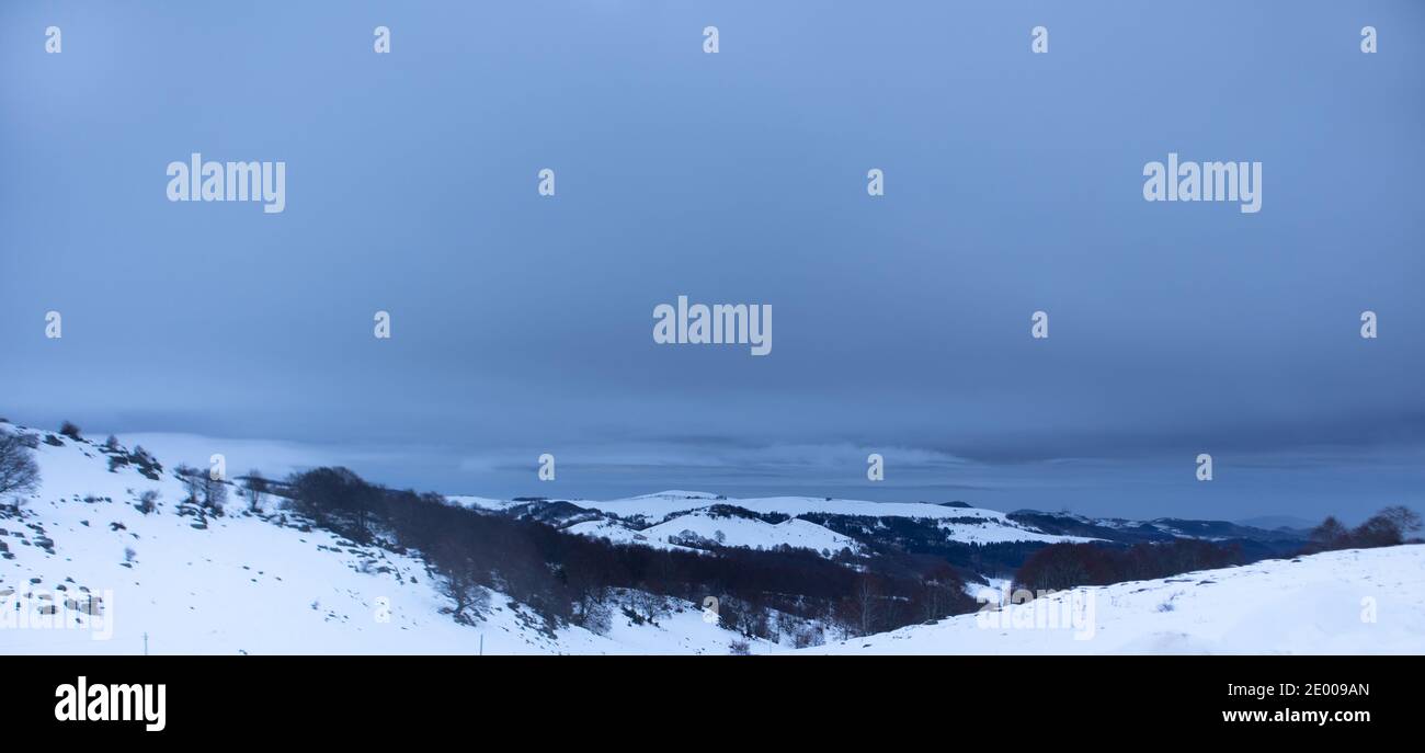 A snowy landscape with a grey, cloudy sky Stock Photo - Alamy