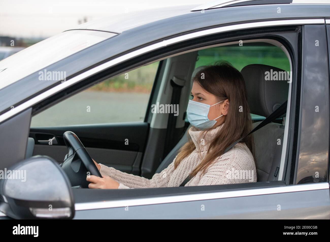 young woman driving a car and wearing a protective mask during covid 19 ...