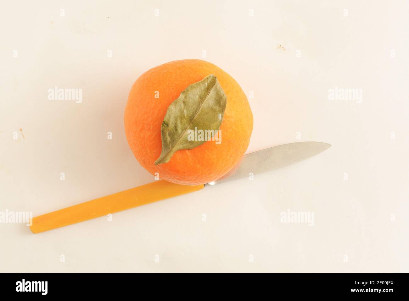 Top view, one whole mandarin with green leaf and a knife for cutting ...