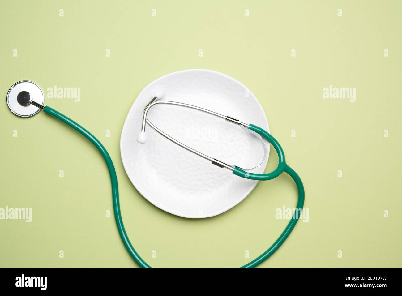 round white ceramic plate and medical stethoscope on green background ...